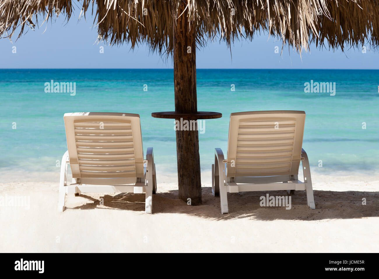 Lounge chairs under sunshade at tranquil beach Stock Photo - Alamy
