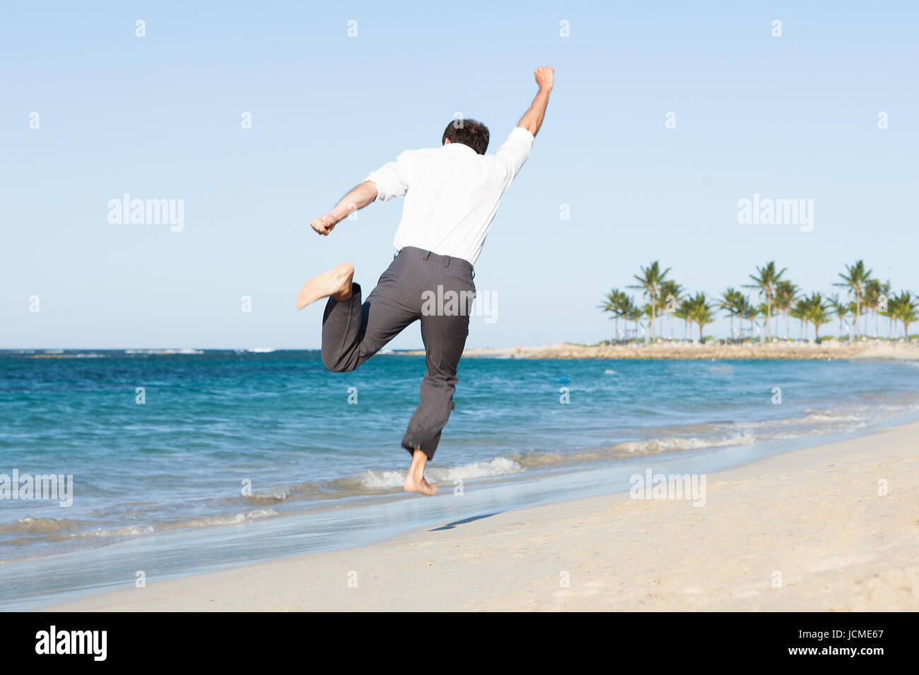 Rear view of happy man jumping at beach Stock Photo - Alamy