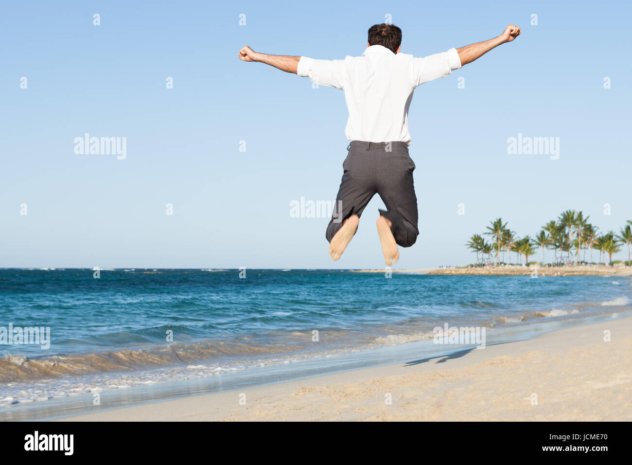 Rear view of happy man jumping at beach Stock Photo - Alamy