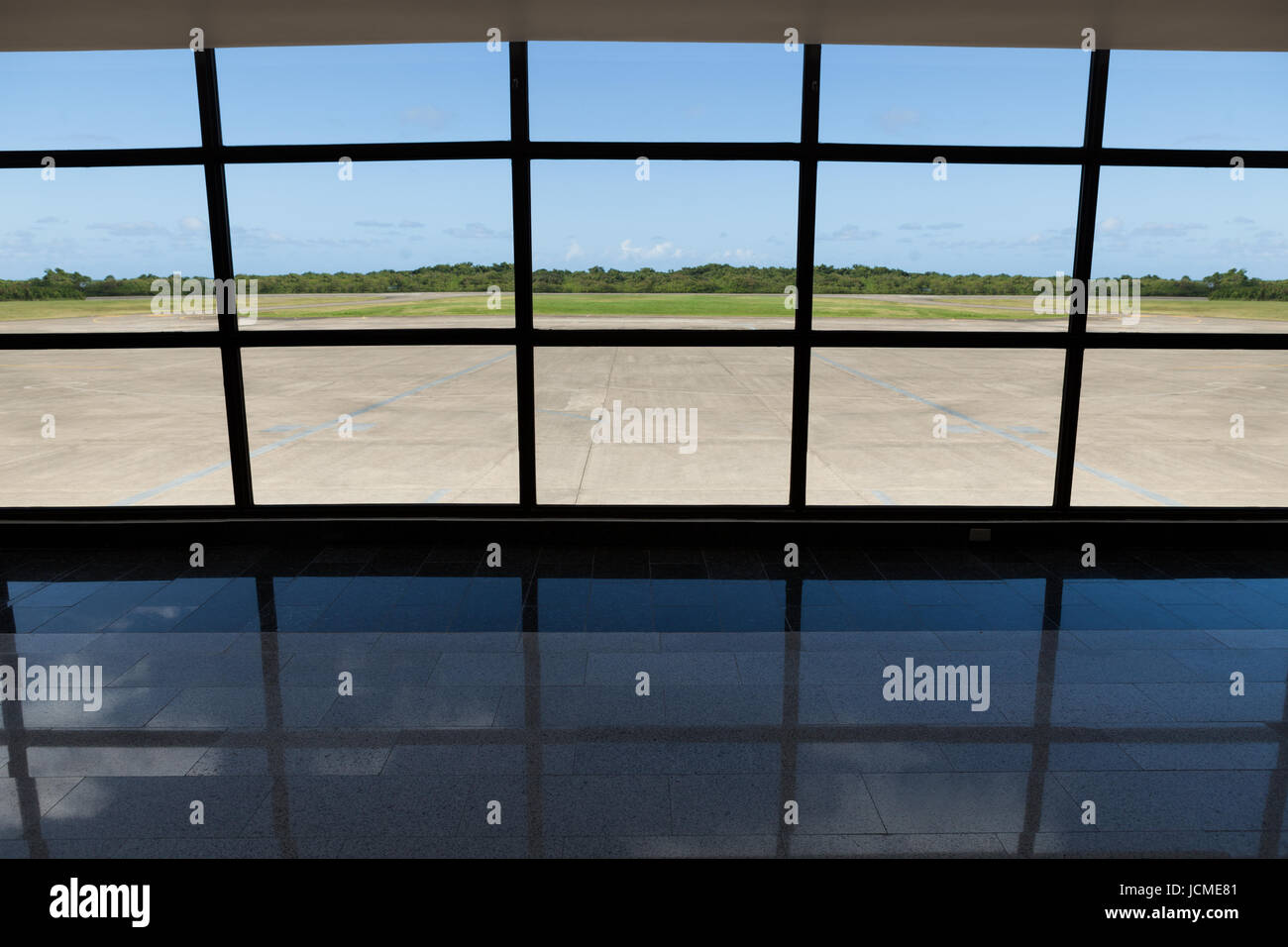 Photo of runway seen through modern airport's window Stock Photo - Alamy