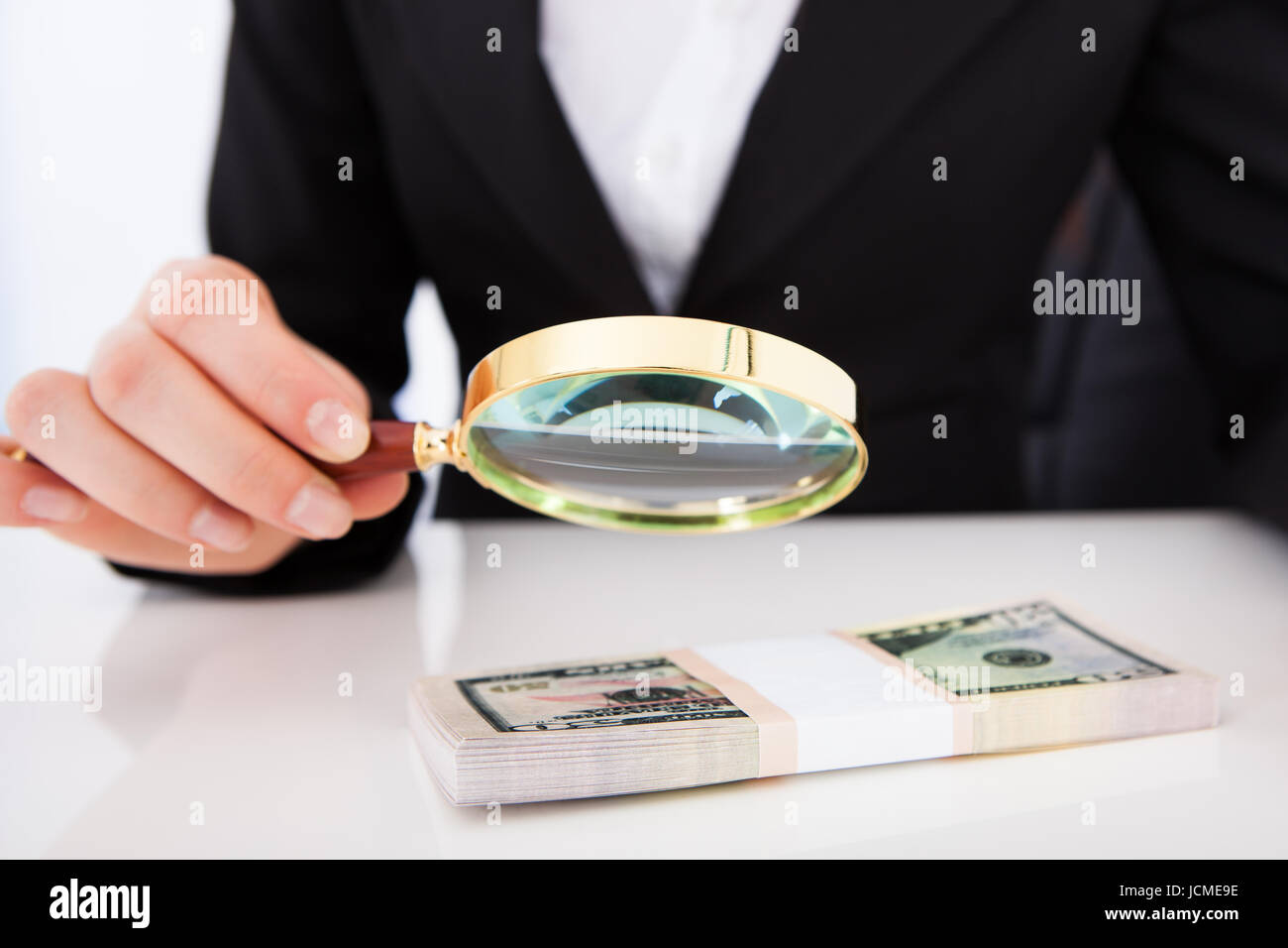 Midsection of young businesswoman scrutinizing dollar bills with ...