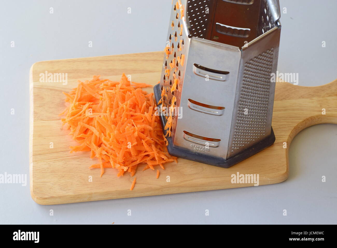 Step by step cooking. Grated carrots with a grater on a wooden cutting ...