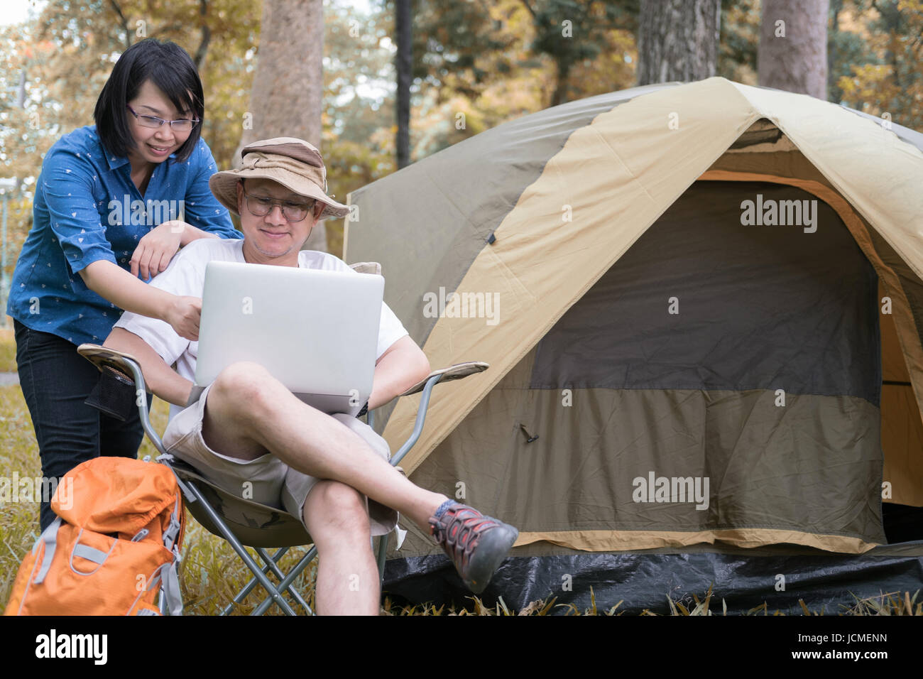 young asian man tourist sitting on chair and using laptop with his ...