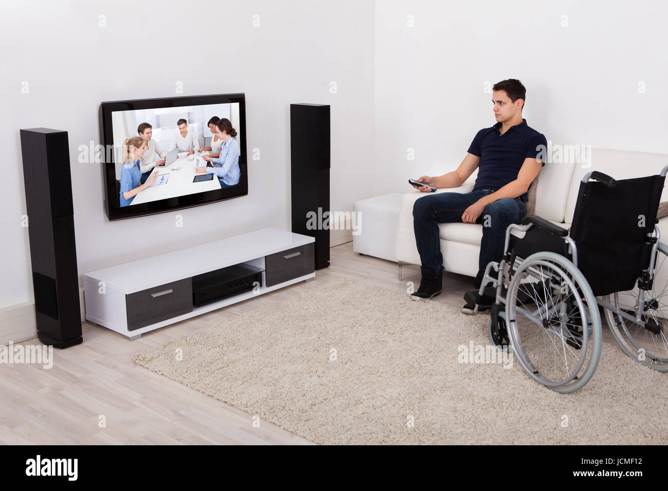 Full length of young handicapped man watching television in living room ...