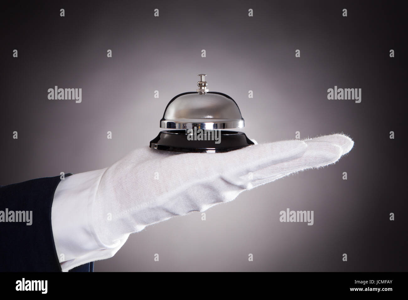Cropped image of bellman holding bell against black background Stock ...
