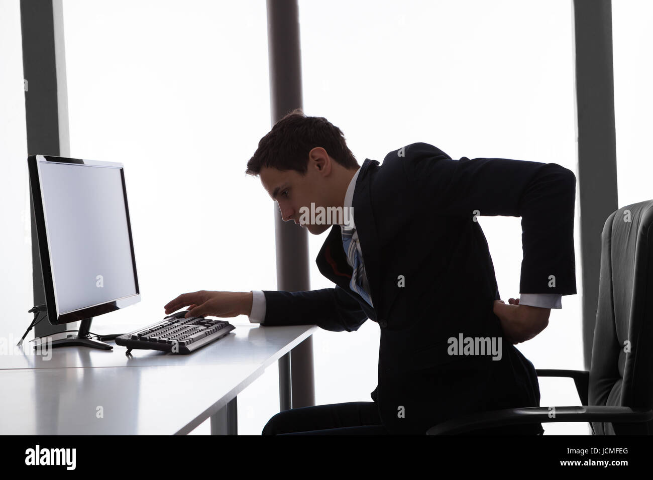 Side view of young businessman suffering from backache in office Stock ...