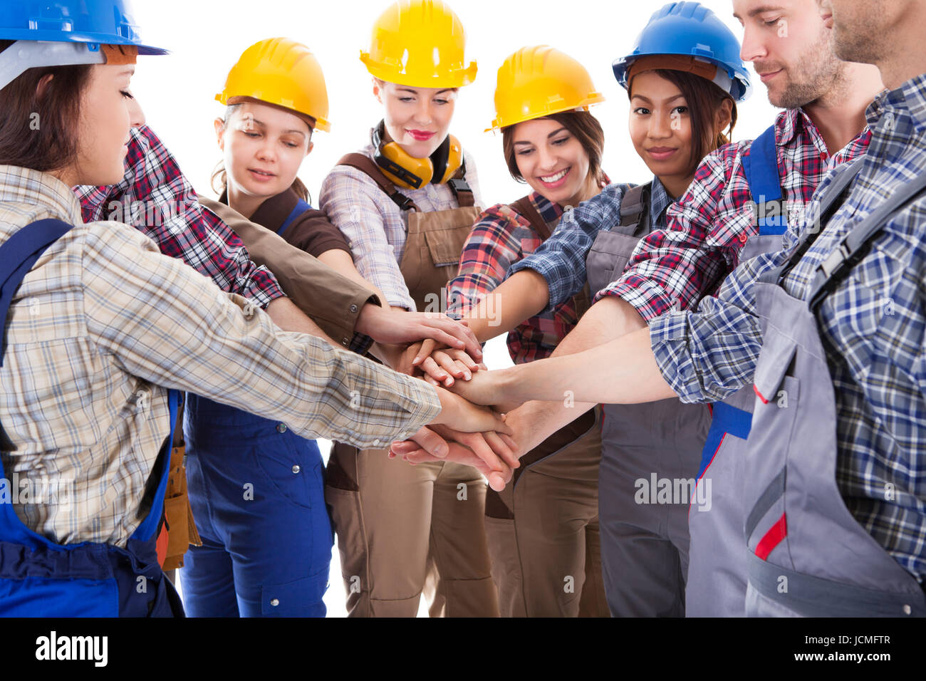 Diverse group of construction workers stacking hands. Isolated on white ...