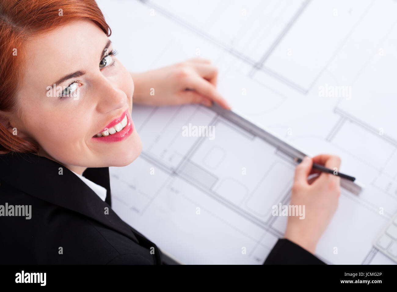 High angle portrait of businesswoman working on blueprint in office ...
