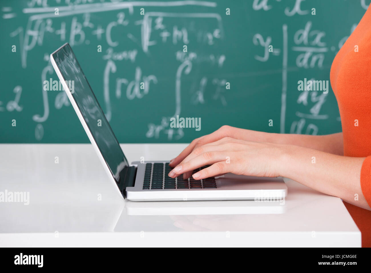 Cropped image of female university student using laptop in classroom ...