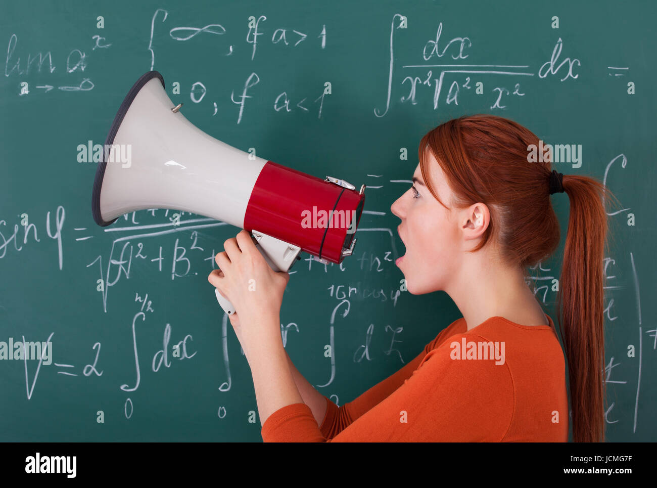 Side view of young female student screaming on megaphone against ...