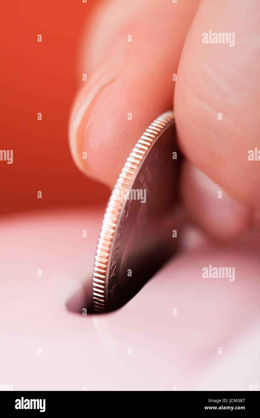 Closeup of woman's hand inserting coin in piggybank Stock Photo - Alamy