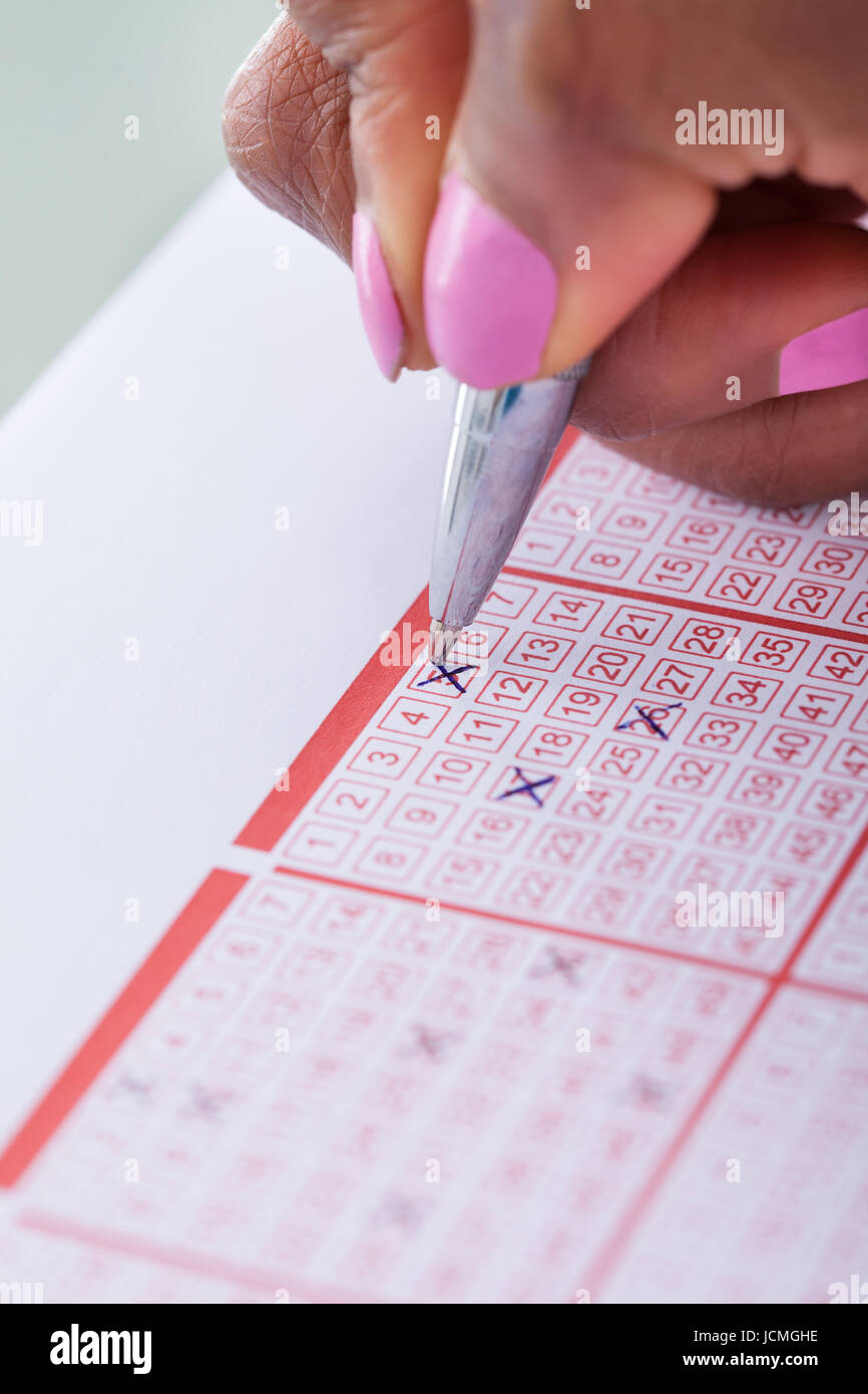Cropped image of woman's hand marking numbers on lottery ticket with ...
