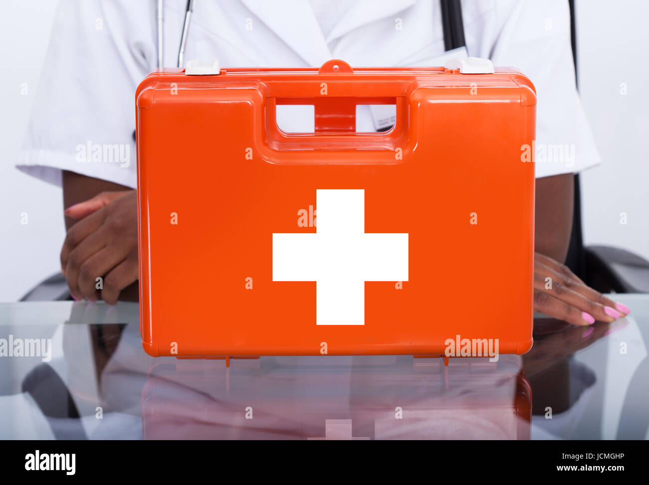 Portrait of confident female doctor with first aid kit at desk in ...