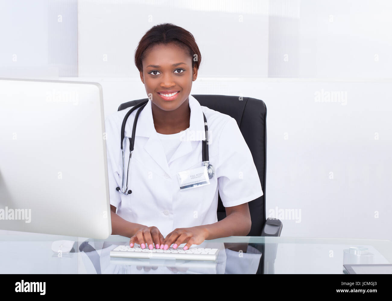 Portrait of confident female doctor using computer at desk in hospital ...