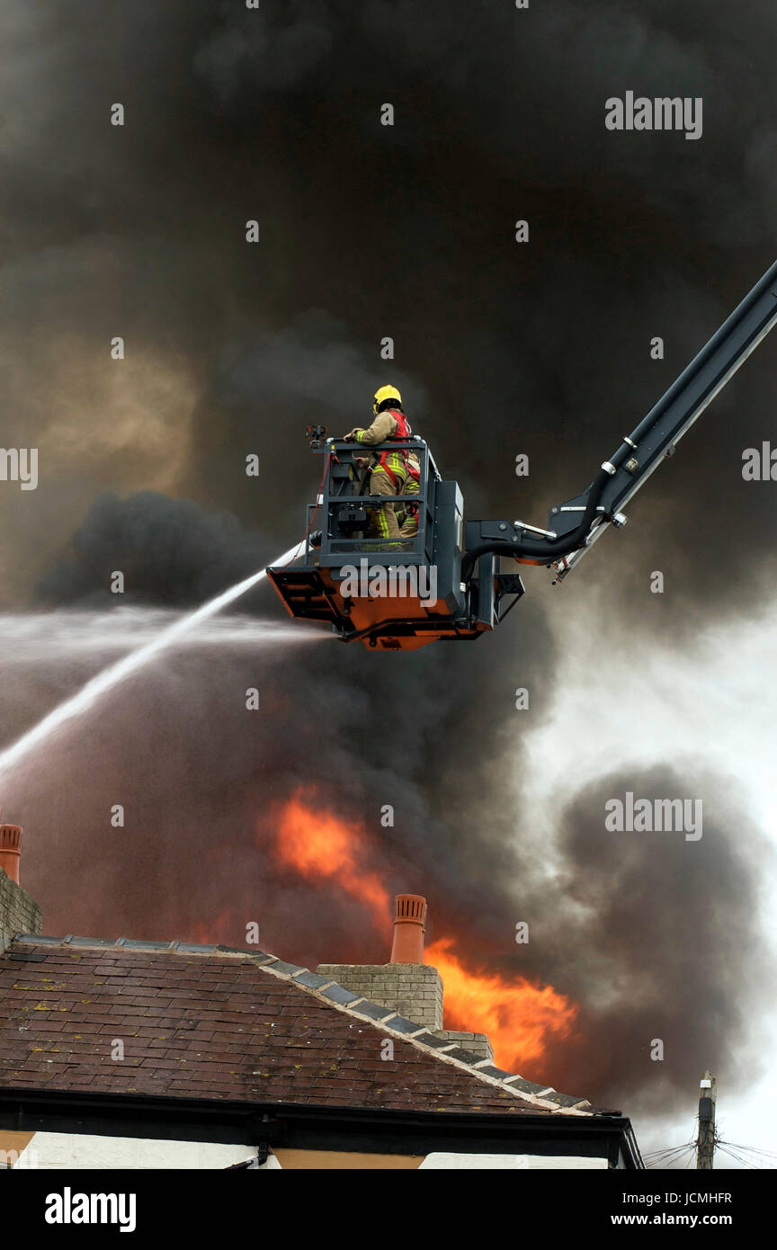 Fire fighters on a platform lift tackle a major industrial fire in a ...