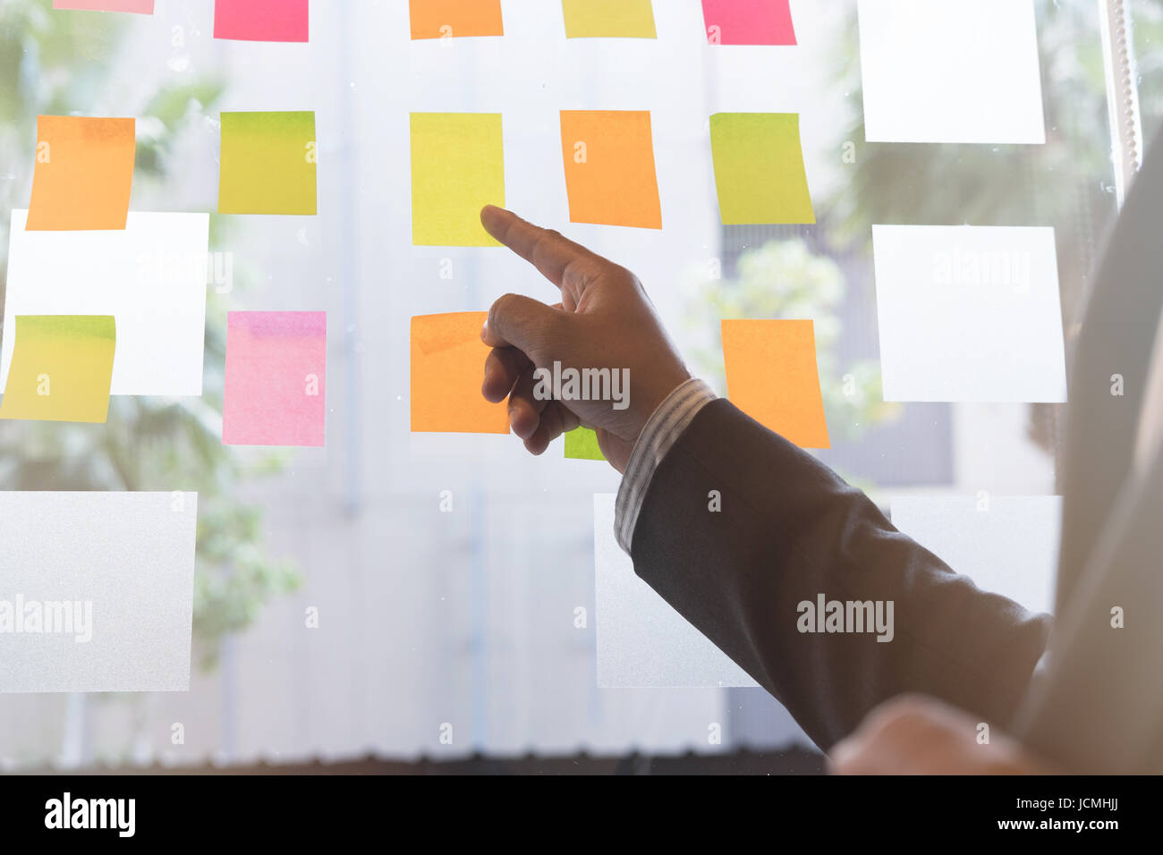 Businessman look at the adhesive notes on glass wall in meeting room ...