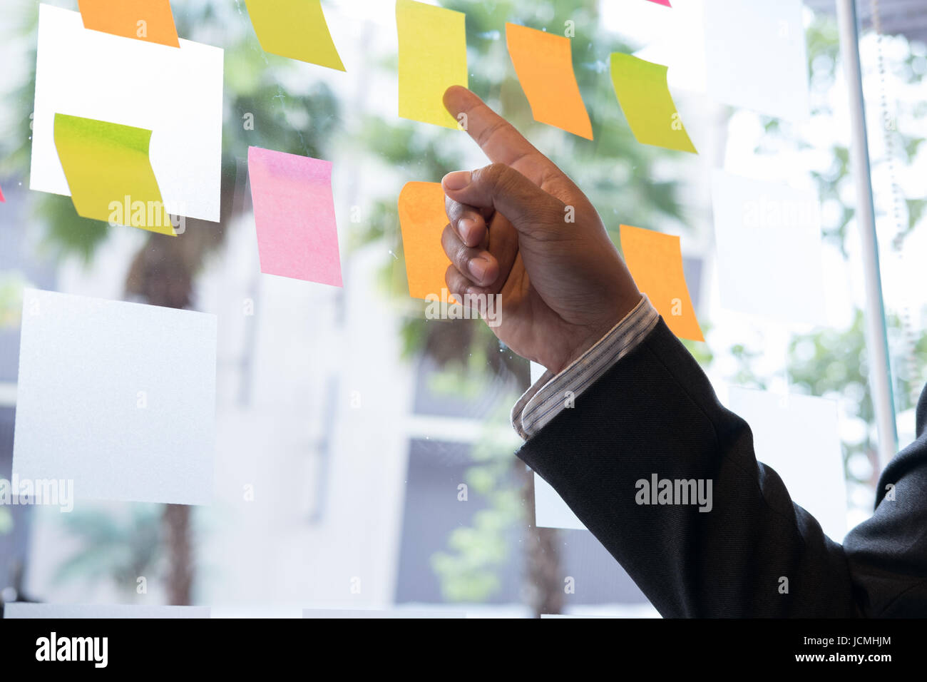 Businessman look at the adhesive notes on glass wall in meeting room ...