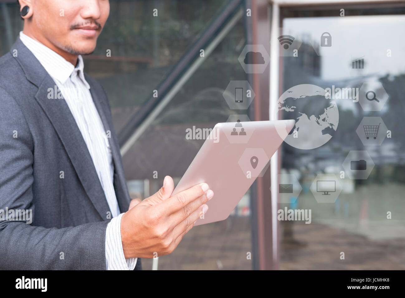 confident businessman in suit holding touch pad while standing outside ...