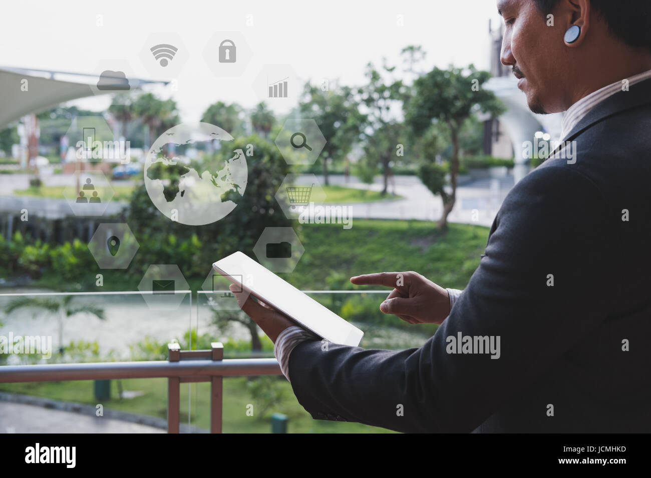 confident businessman in suit holding touch pad while standing outside ...