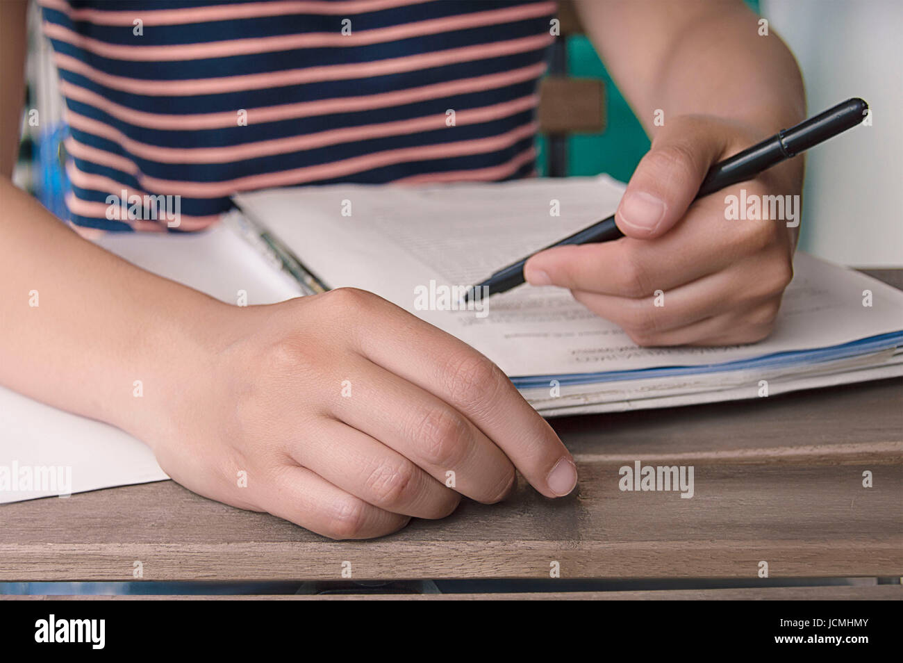 Person writing a document with hand in foreground on blurry background ...