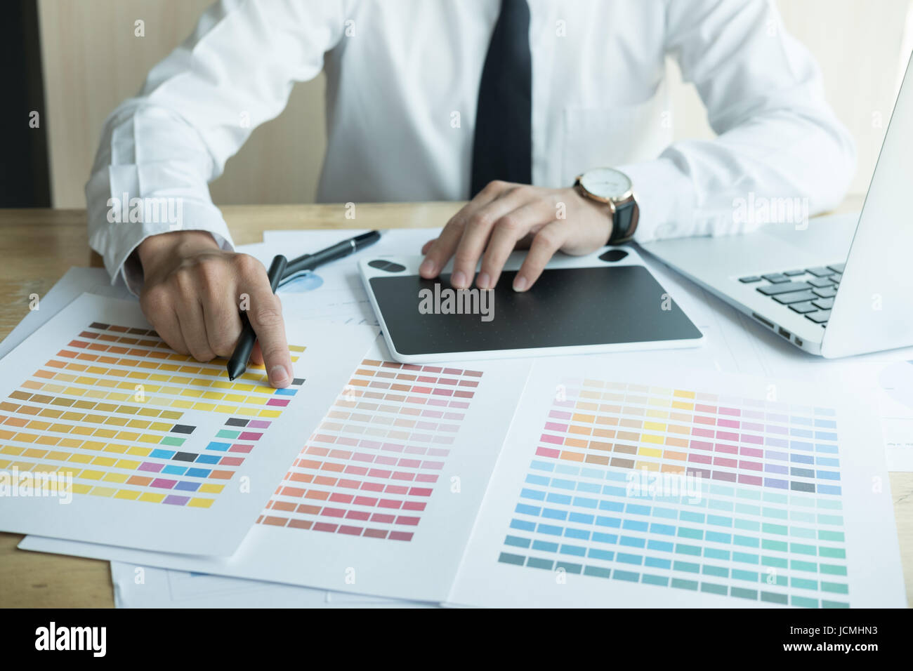 young male graphic designer working with computer and color swatch ...