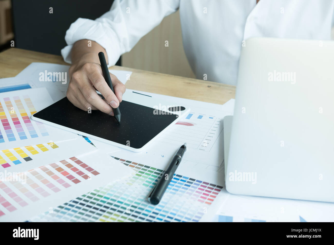 young male graphic designer working with computer and color swatch ...
