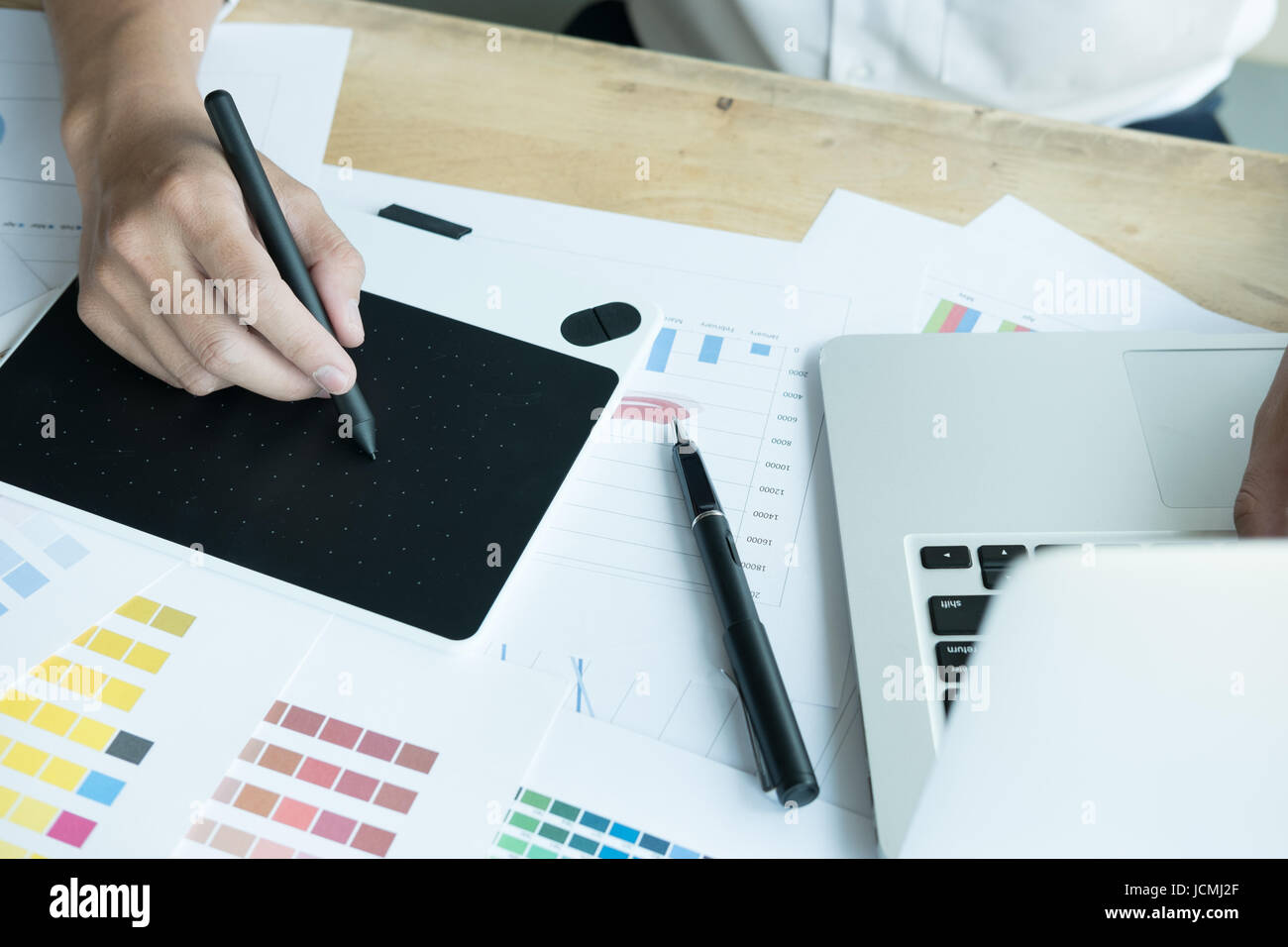 young male graphic designer working with computer and color swatch ...