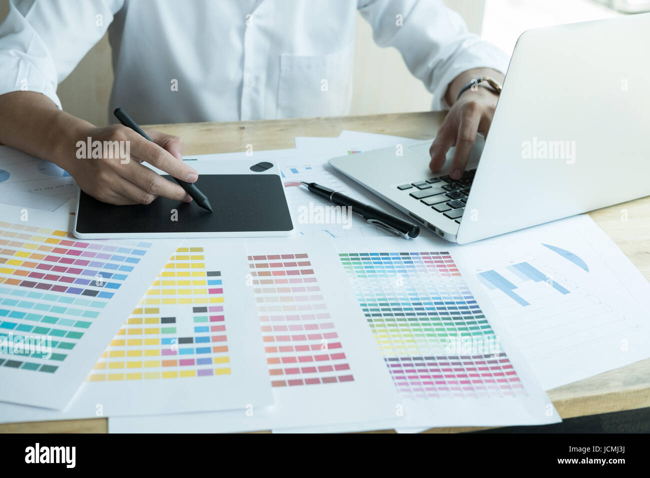young male graphic designer working with computer and color swatch ...