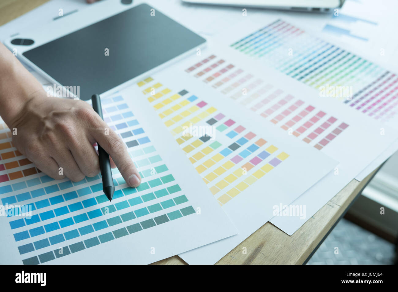 young male graphic designer working with computer and color swatch ...