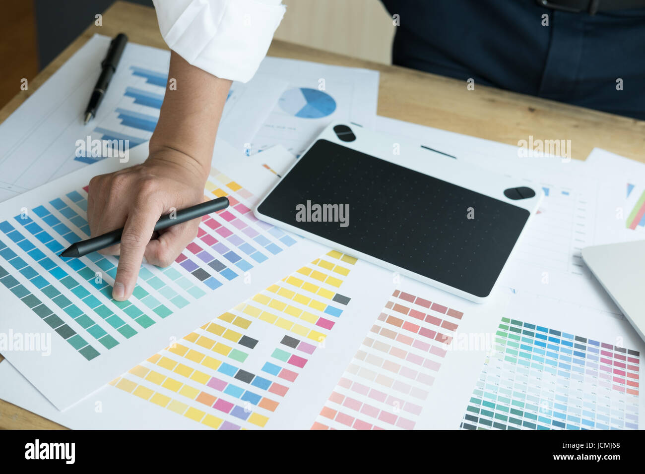 young male graphic designer working with computer and color swatch ...