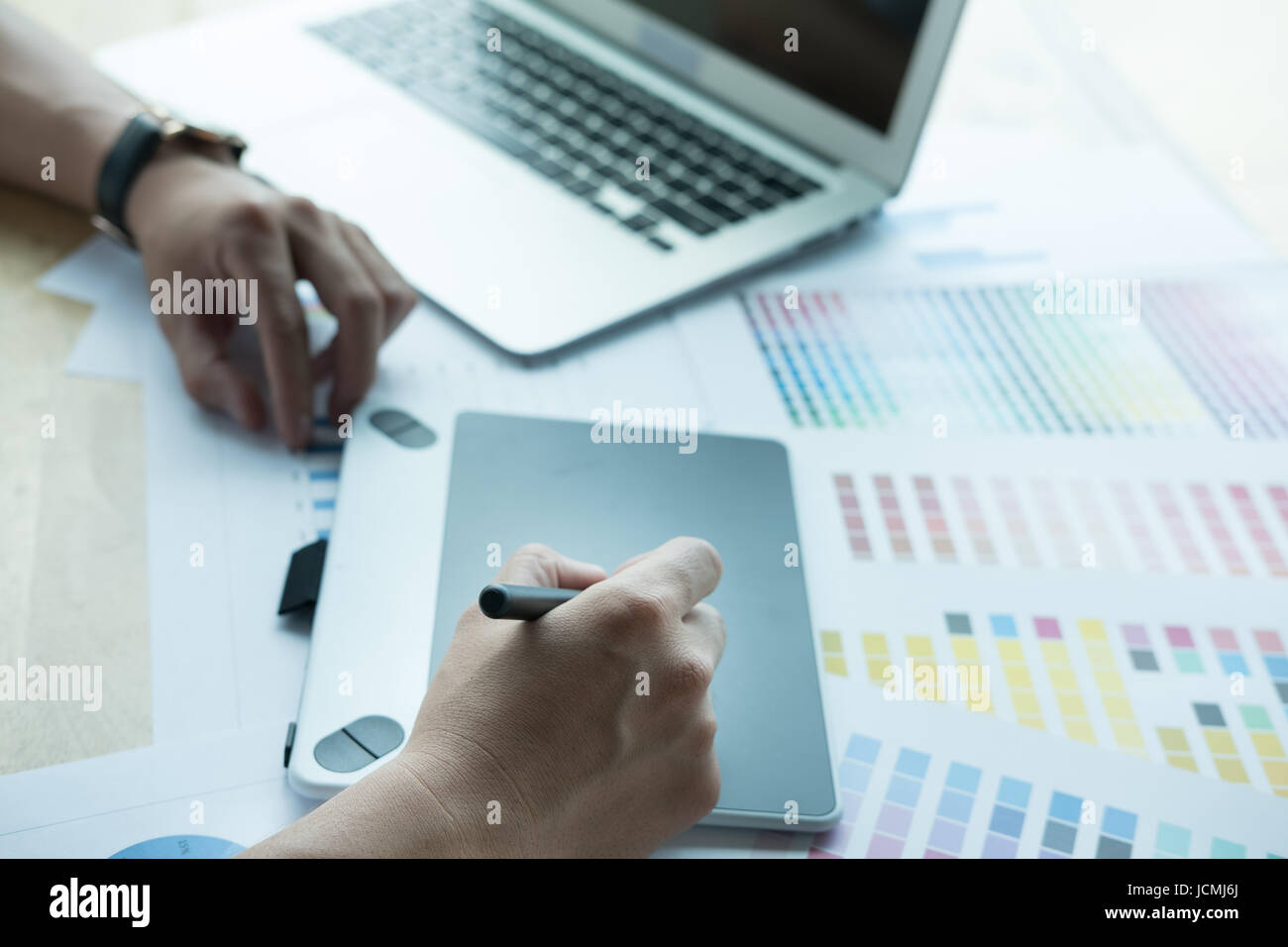 young male graphic designer working with computer and color swatch ...