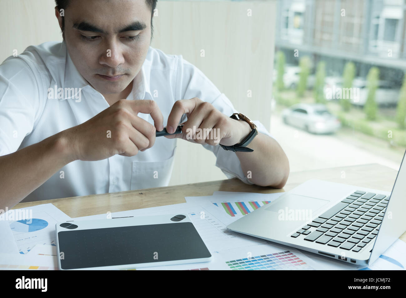 young male graphic designer working with computer and color swatch ...