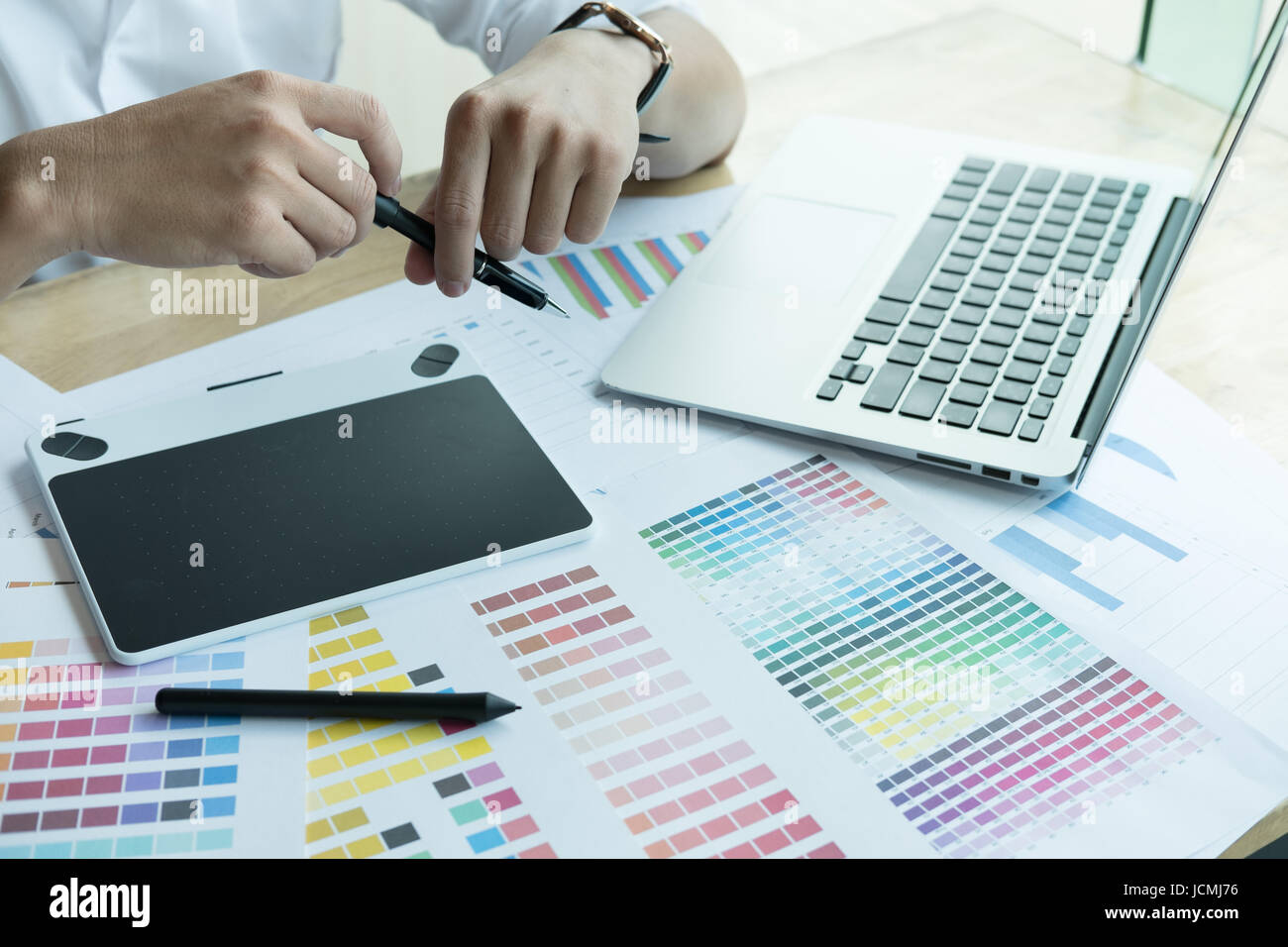 young male graphic designer working with computer and color swatch ...