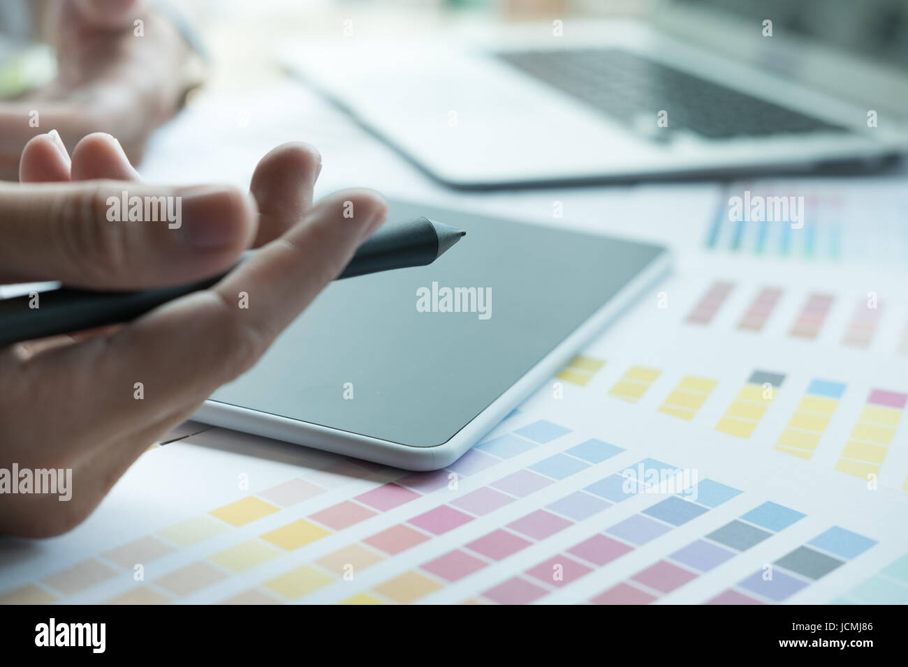 young male graphic designer working with computer and color swatch ...