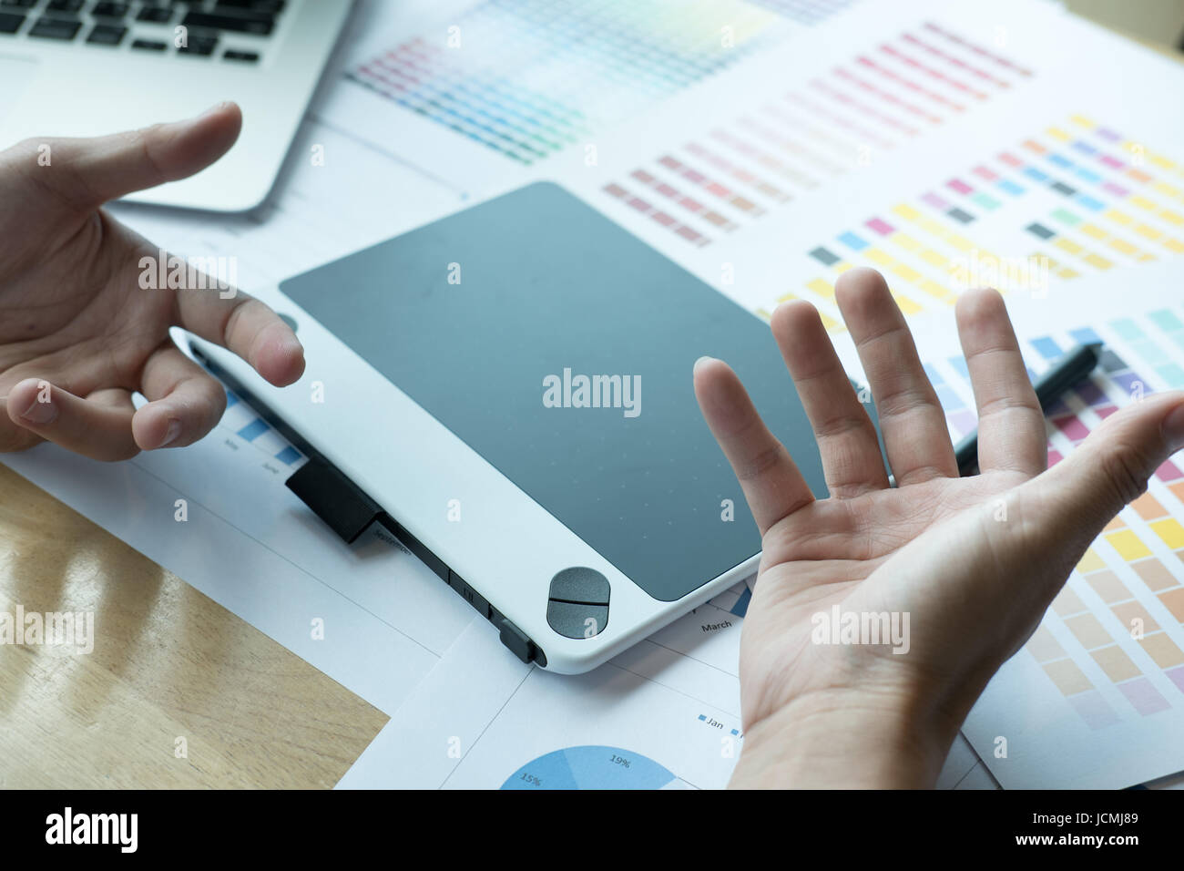 young male graphic designer working with computer and color swatch ...