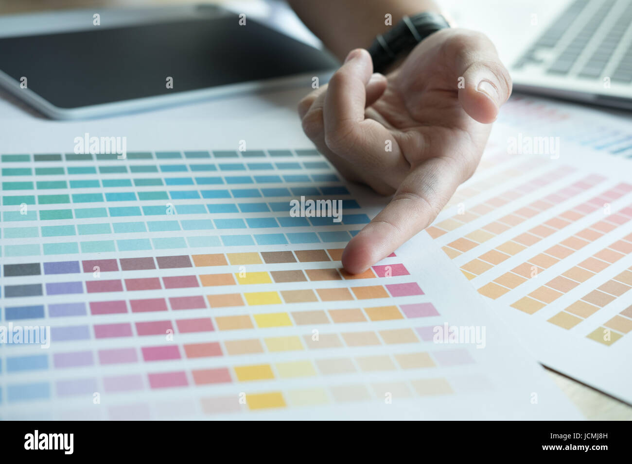 young male graphic designer working with computer, color swatch sample ...