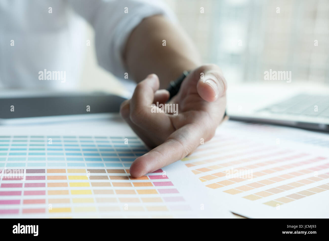 young male graphic designer working with computer, color swatch sample ...