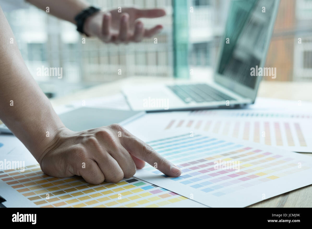 young male graphic designer working with computer, color swatch sample ...