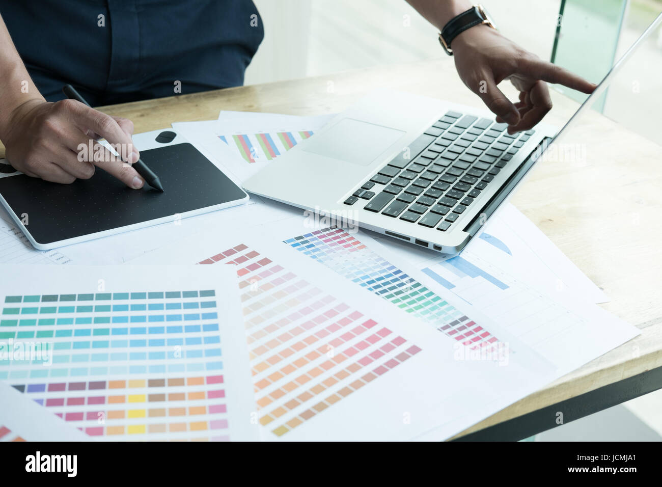 young male graphic designer working with computer and color swatch ...