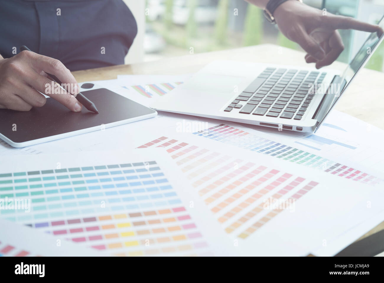 young male graphic designer working with computer and color swatch ...