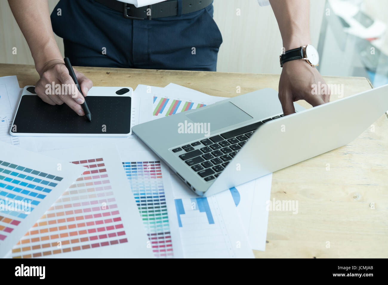 young male graphic designer working with computer and color swatch ...
