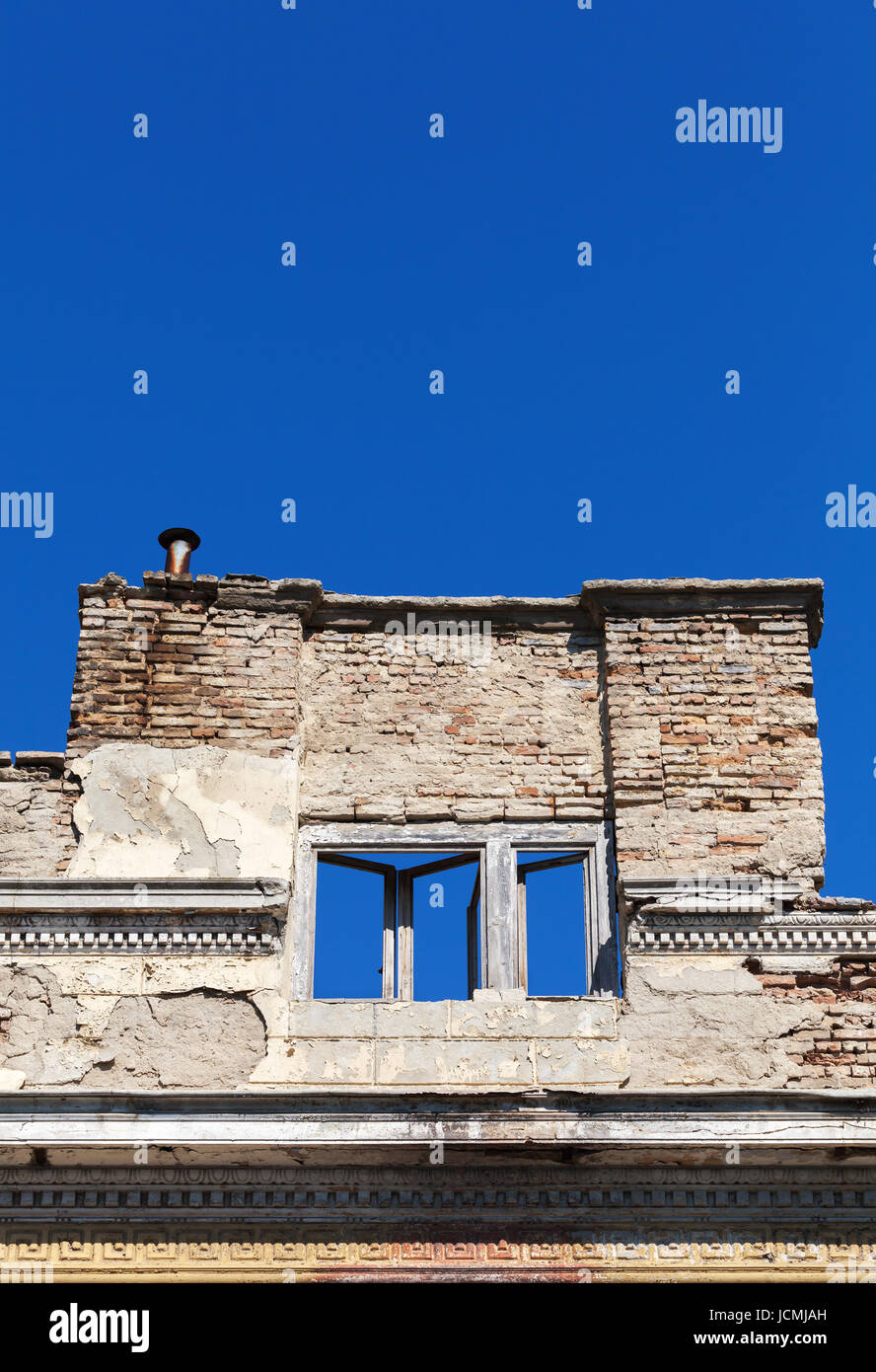 Collapsing facade of an old house with empty windows under blue sky ...