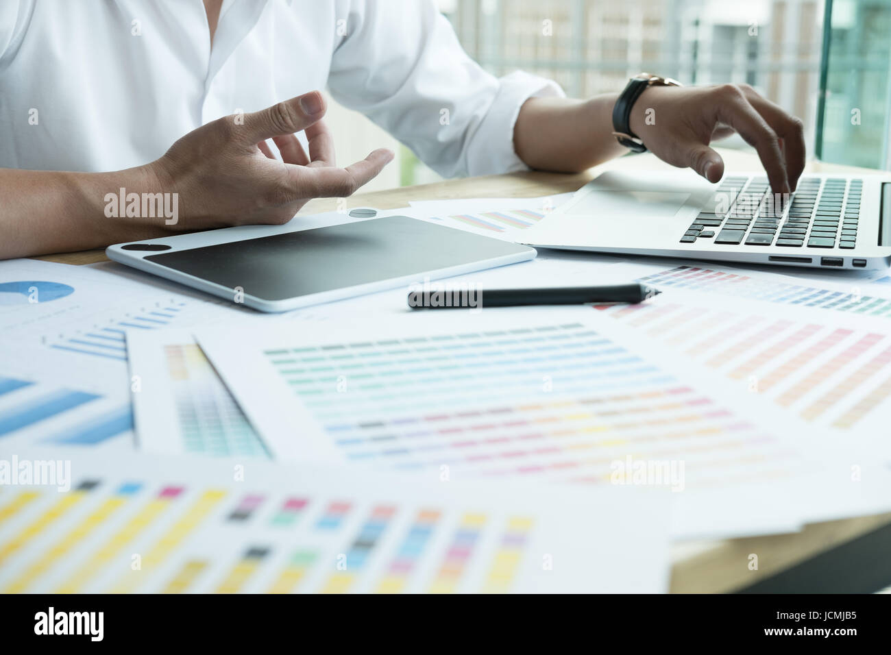 young male graphic designer working with computer, color swatch sample ...