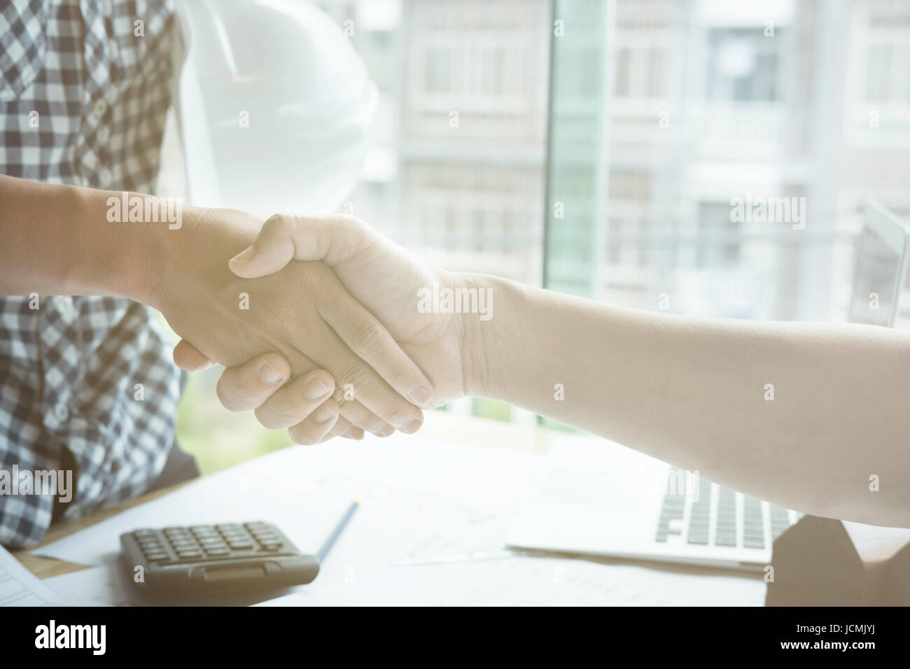 young architect and customer shaking hands at workplace. Engineer ...