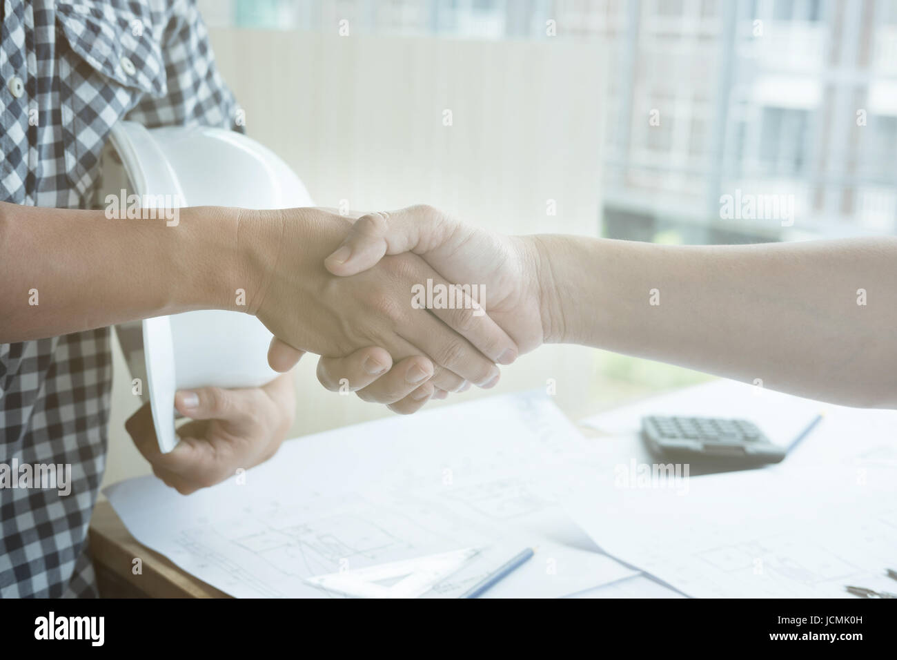 young architect and customer shaking hands at workplace. Engineer ...