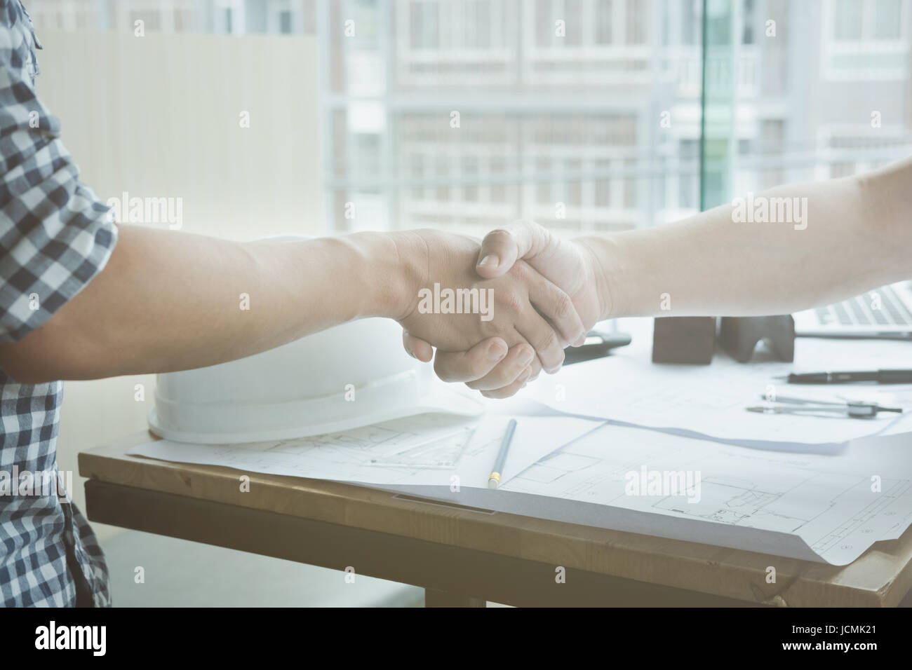young architect and customer shaking hands at workplace. Engineer ...