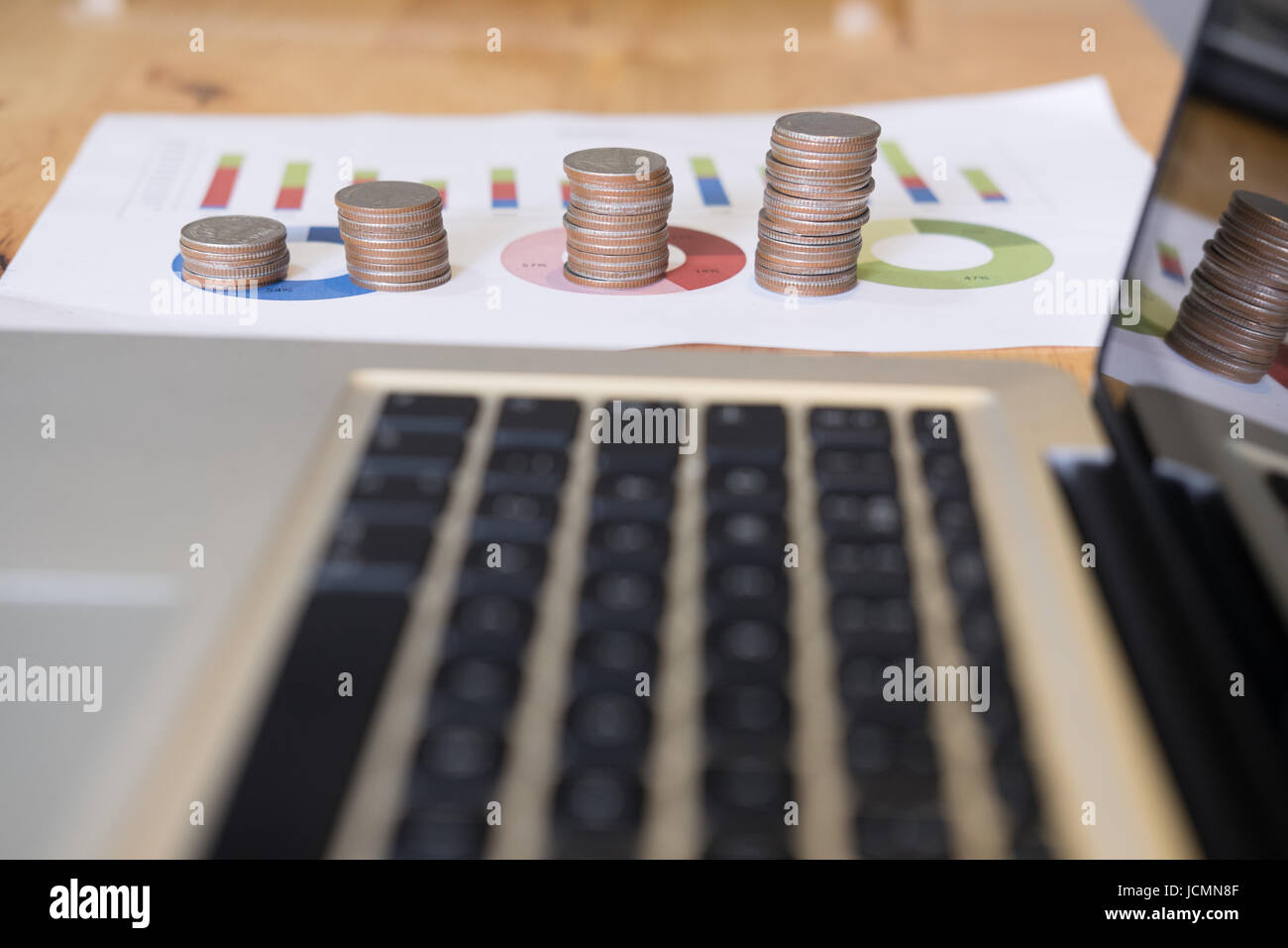 computer and increasing pile of coins on graph and chart. financial ...