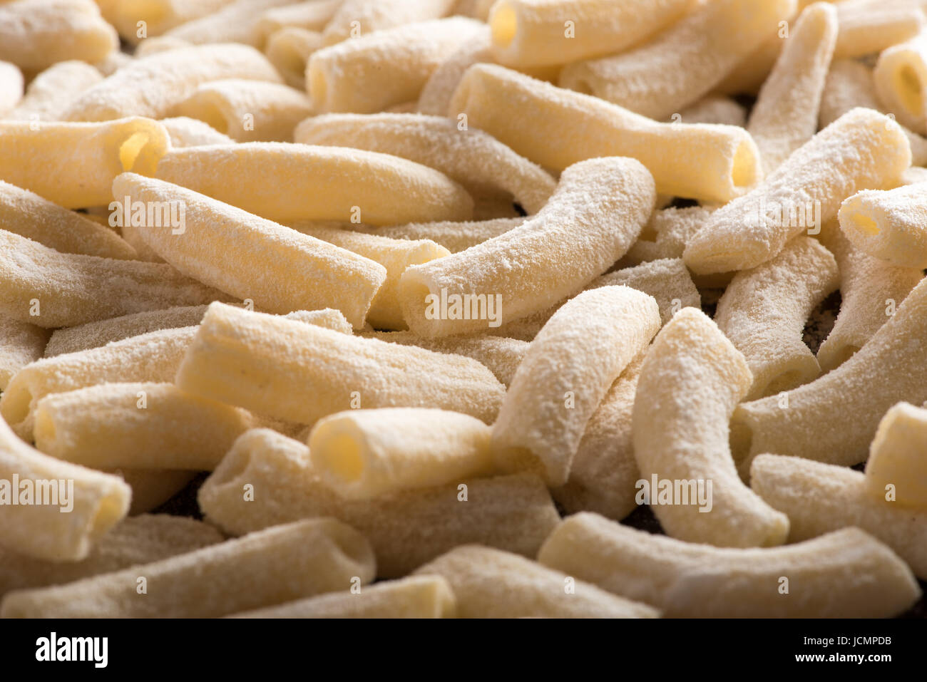 Close-up view of raw handmade maccheroncini pasta in flour lying on ...