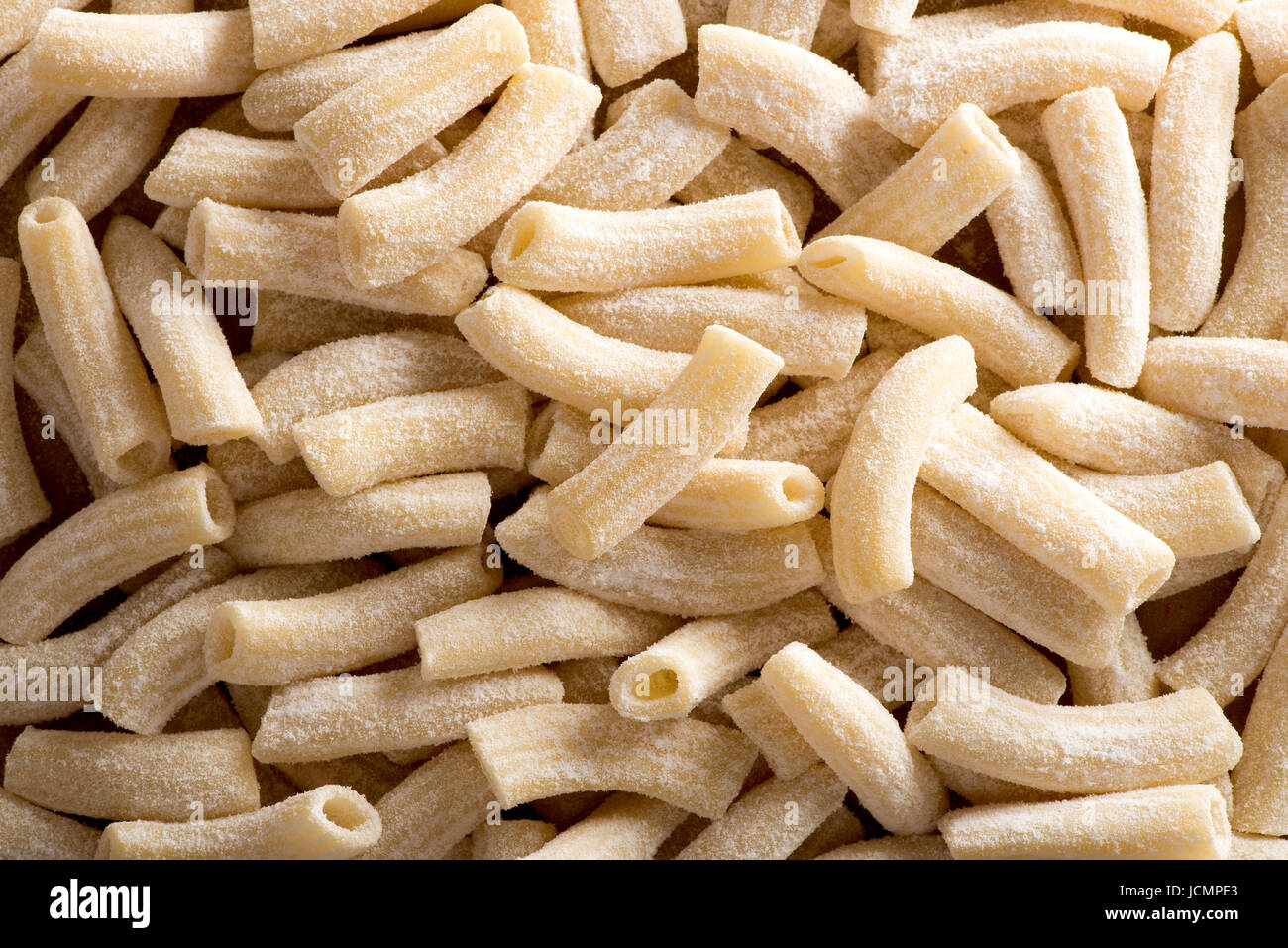 From above close-up view of raw handmade maccheroncini pasta in flour ...