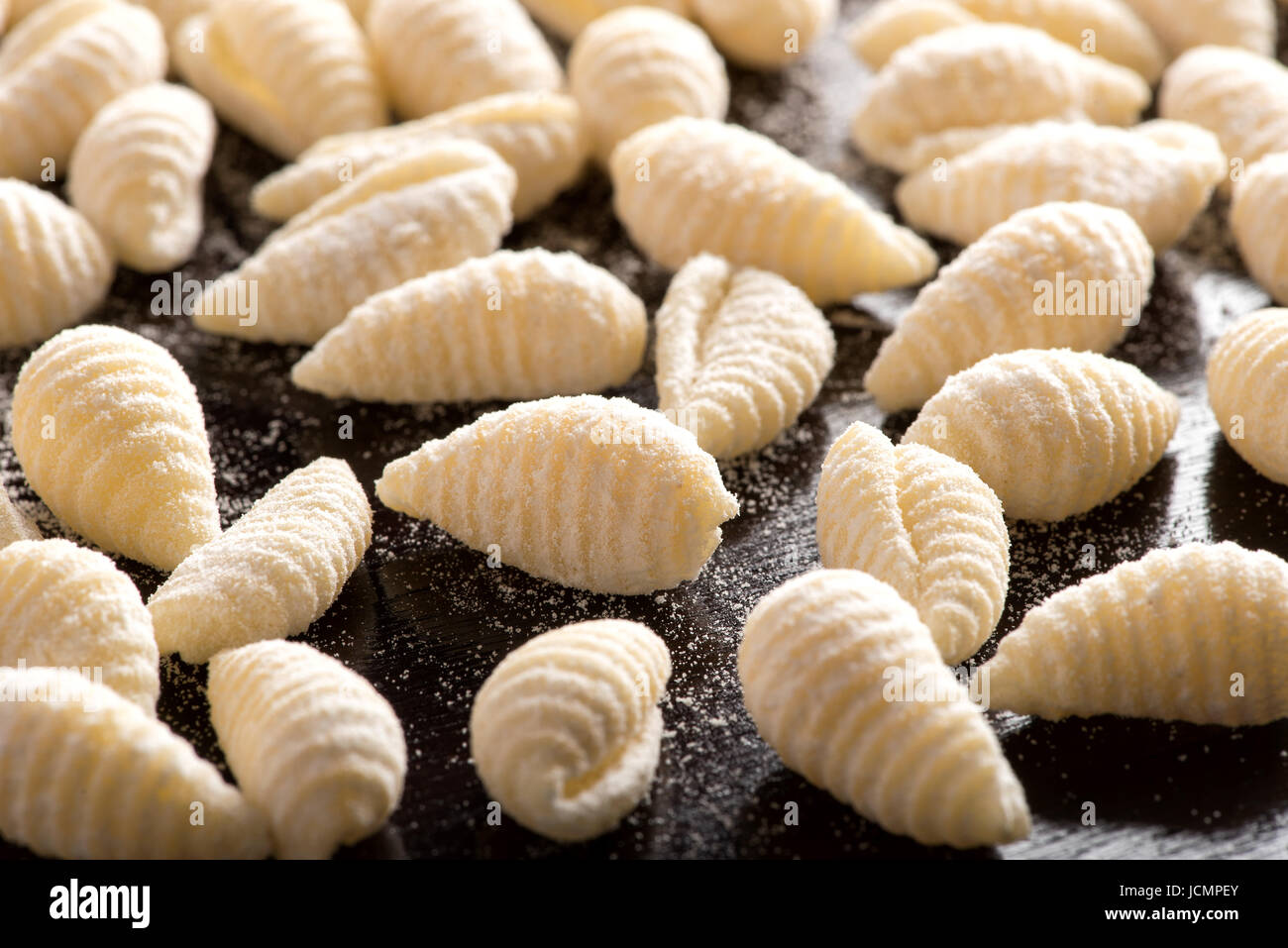 Close-up of raw handmade Italian pasta of shells shape lying on black ...